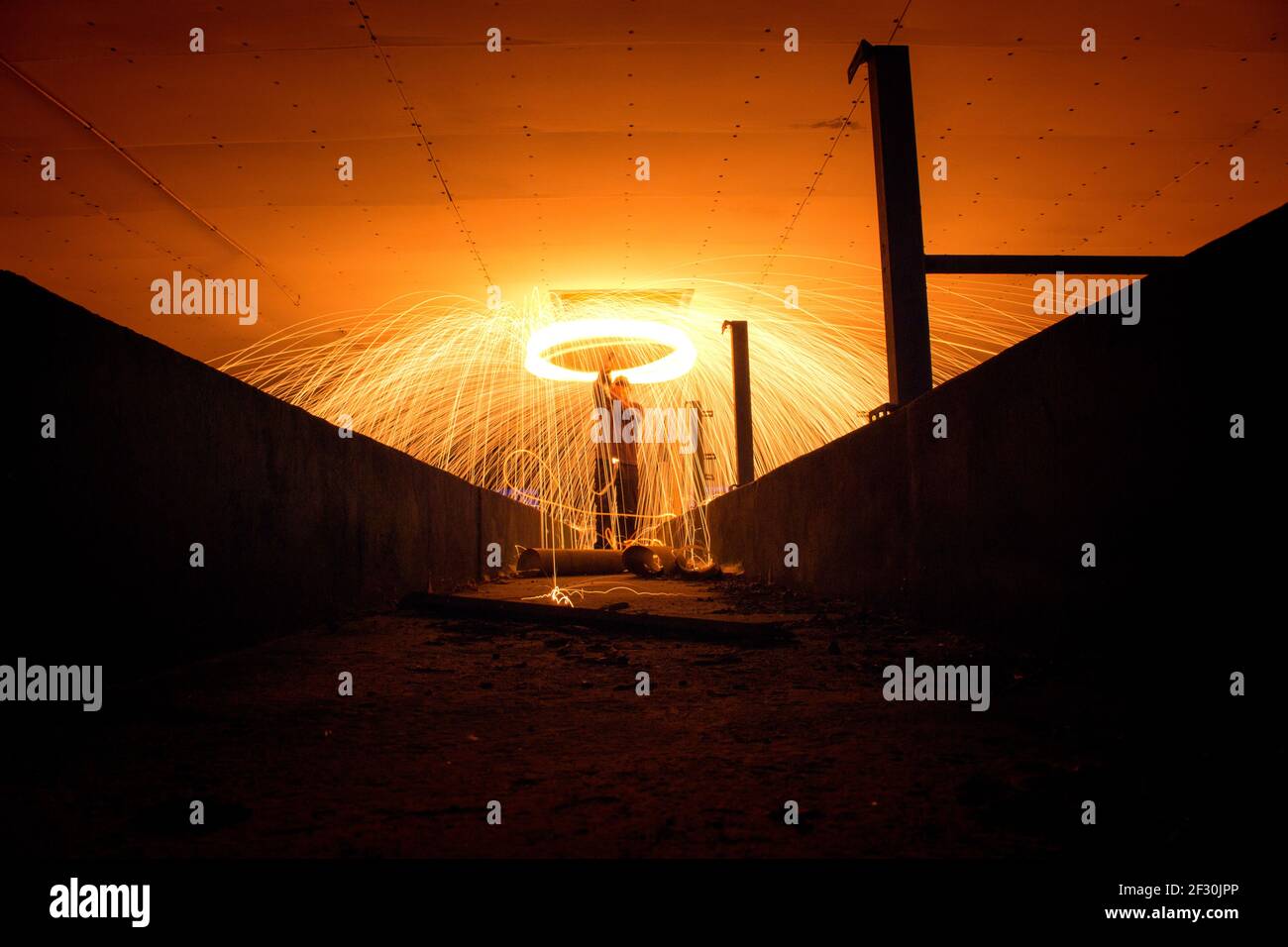 A person spinning sparkling steel wool with long exposure in a building ...