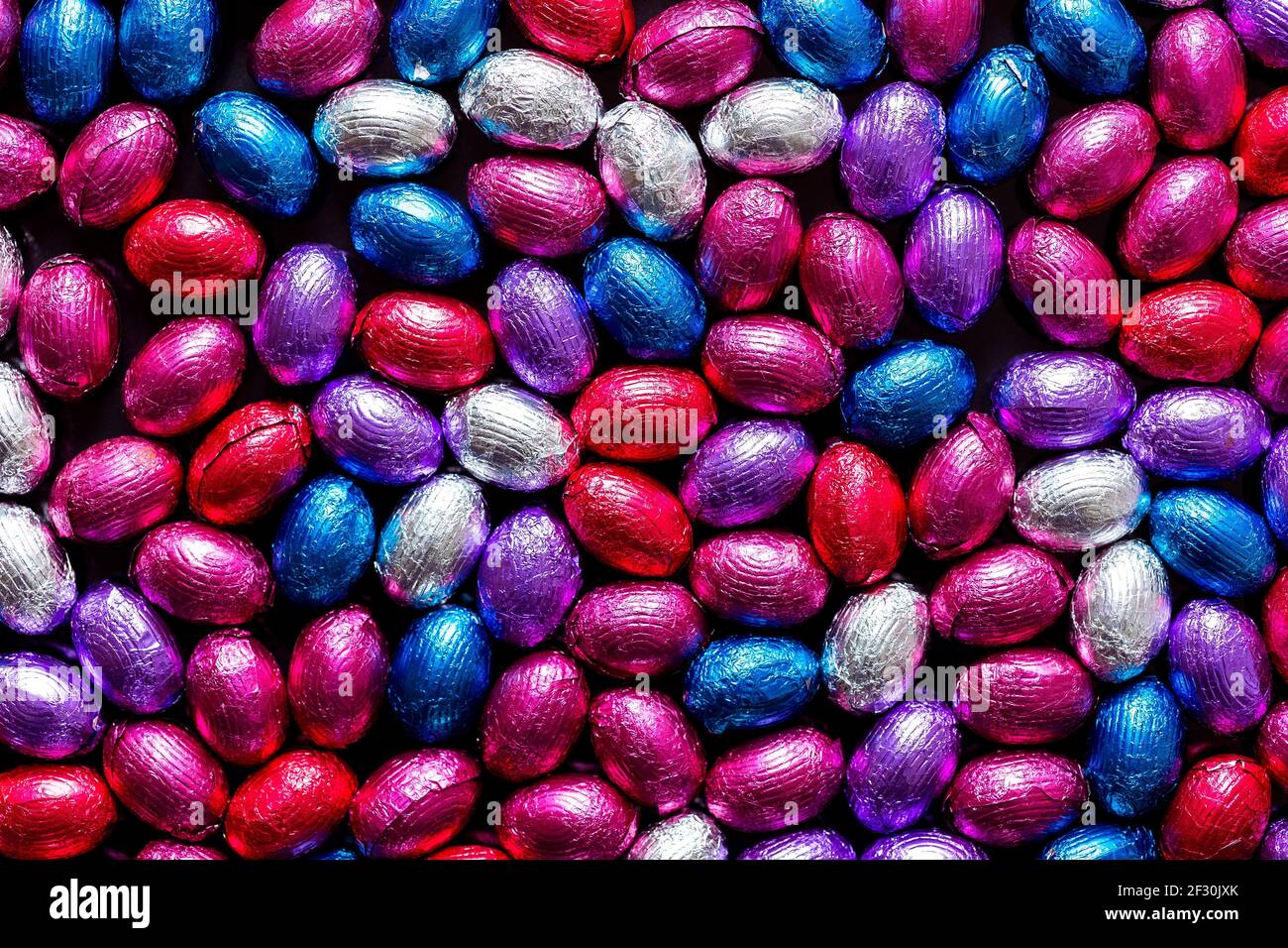 A portrait of a lot of colorful chocolate easter eggs wrapped in ...