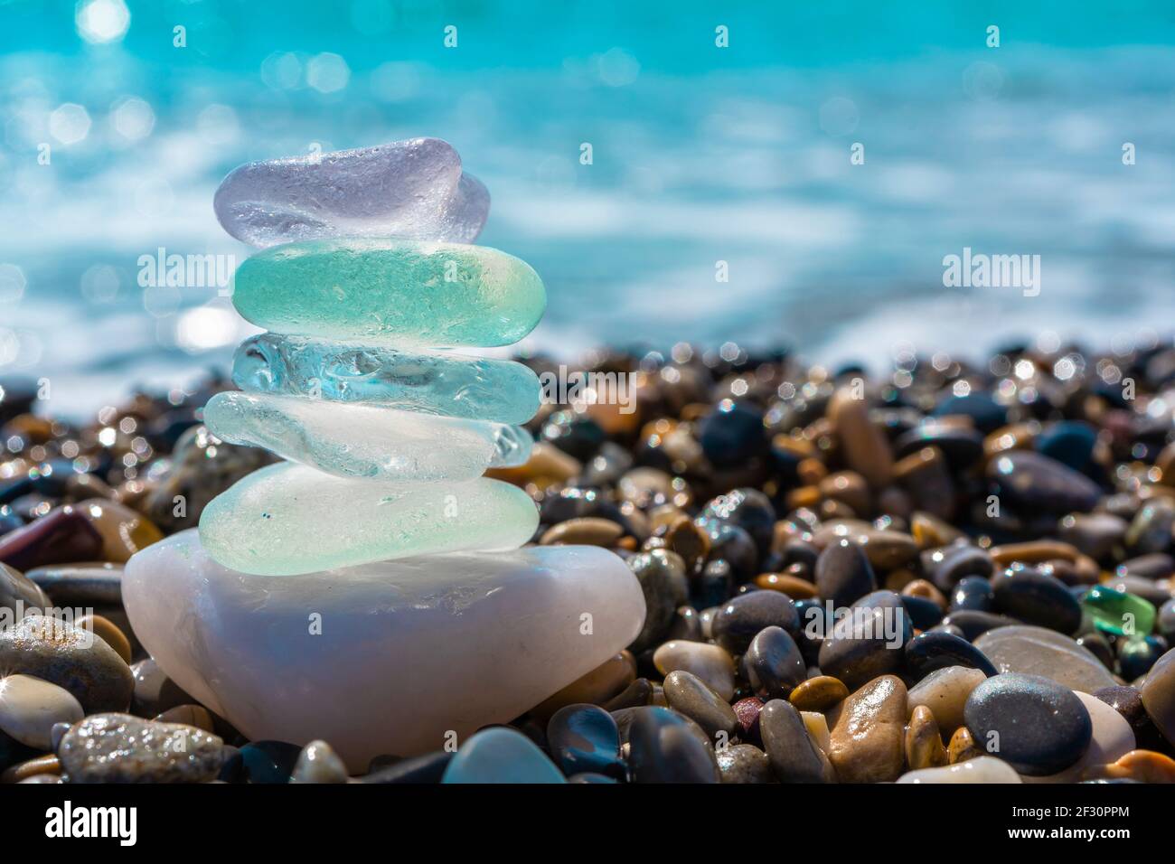 Sea glass stones arranged in a balance pyramid on the beach. Beautiful ...