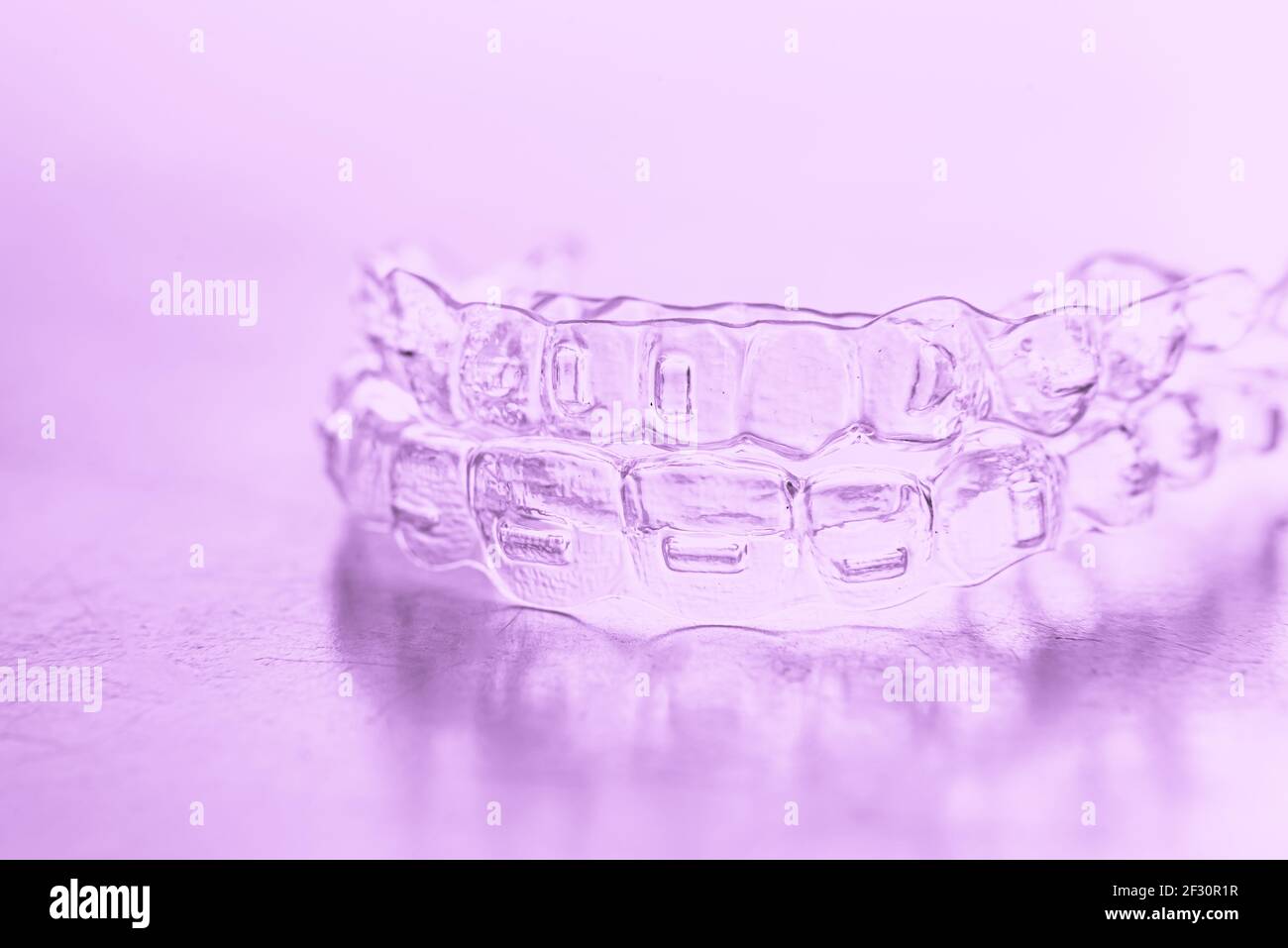 Invisible aligner teeth retainers on a pink background Stock Photo - Alamy