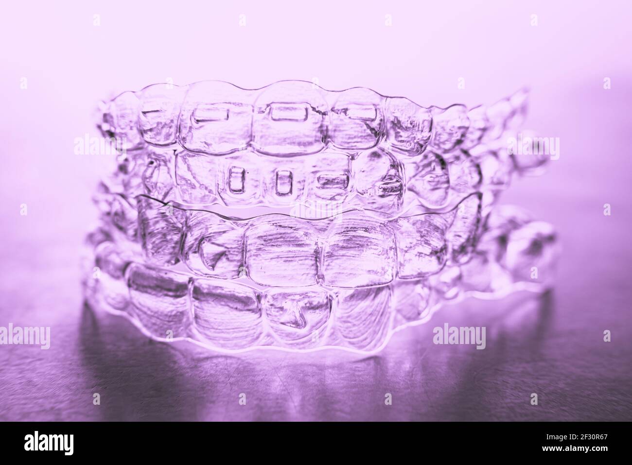 Invisible aligner teeth retainers on a pink background Stock Photo - Alamy