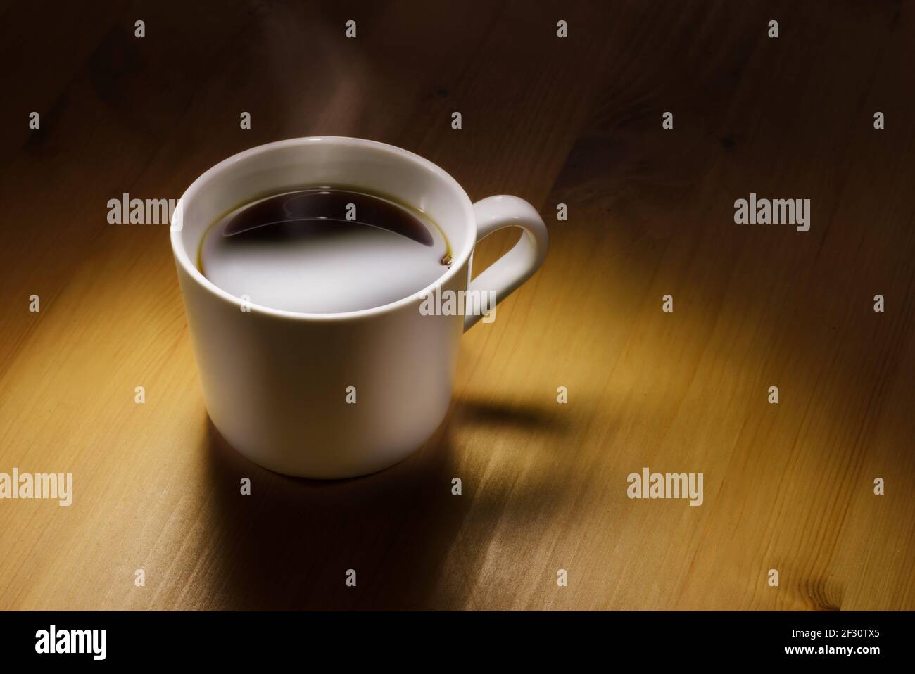 Cup of coffee under a spotlight and on a wooden ground Stock Photo - Alamy