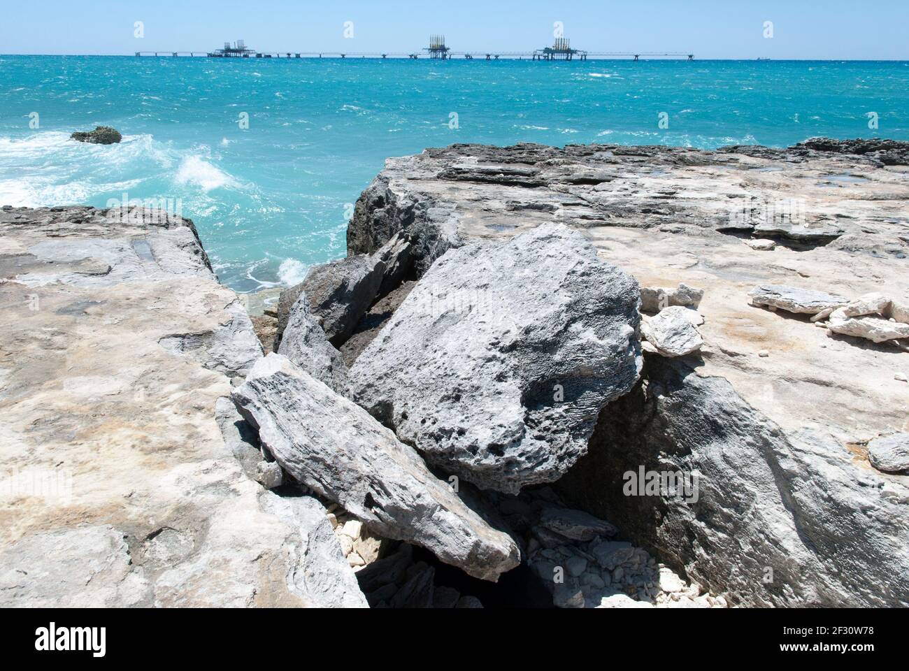 The view of collapsed rocks on Grand Bahama island beach and a wet dock ...