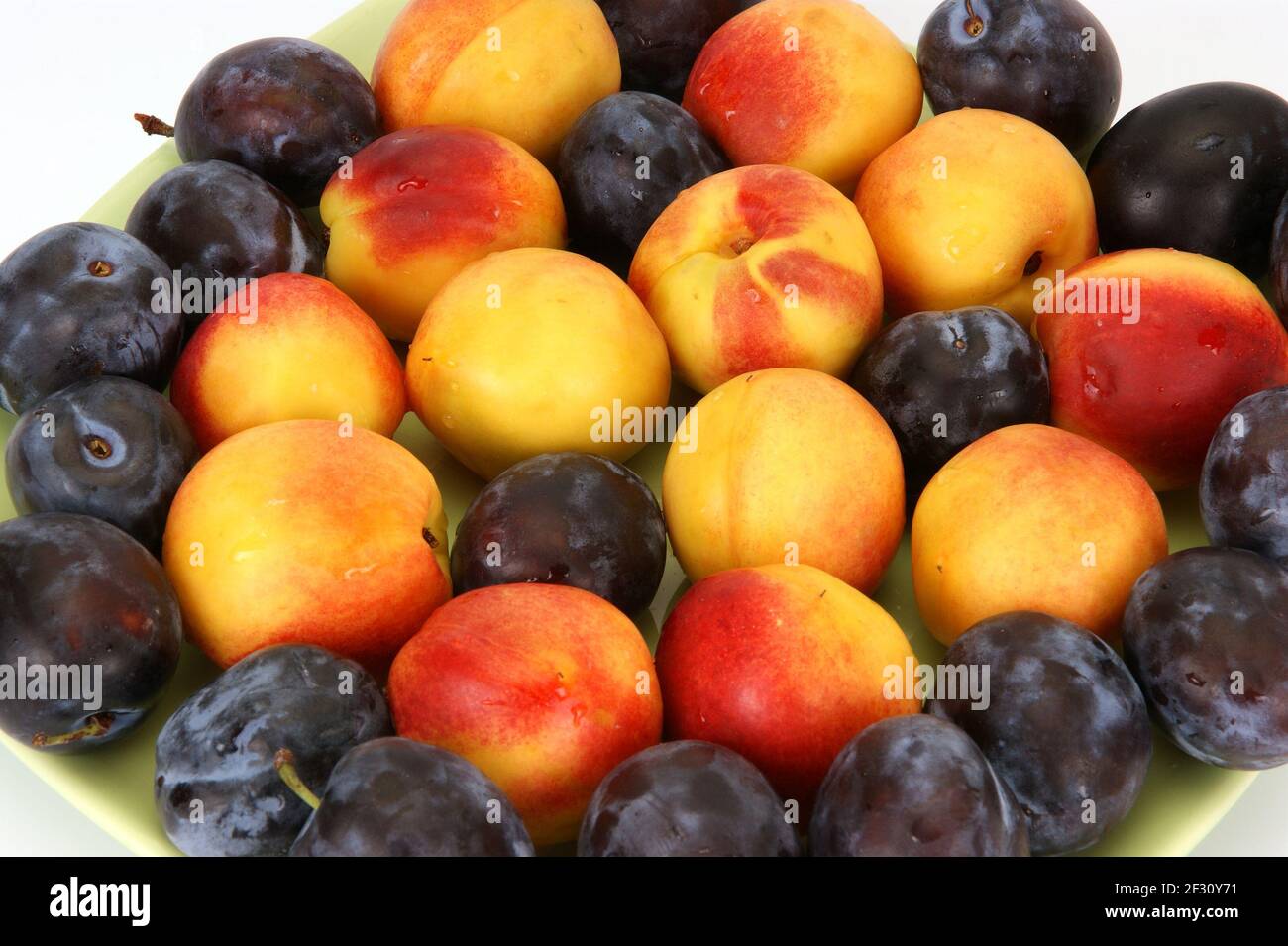 Still life with natural ripe plums and peaches on a white background ...
