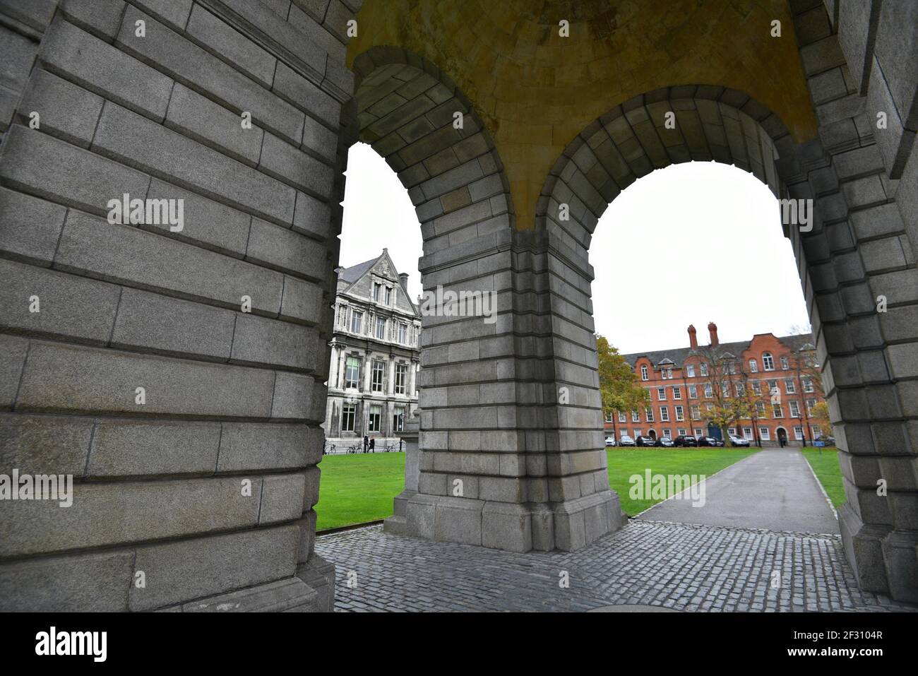 Exterior view of Trinity College through ancient stone arches in Dublin ...