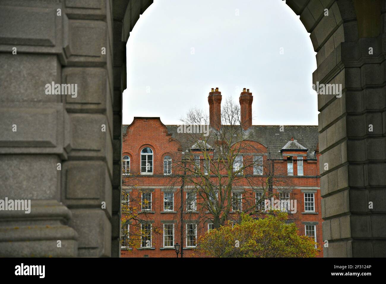 Exterior view of Trinity College through ancient stone arches in Dublin ...