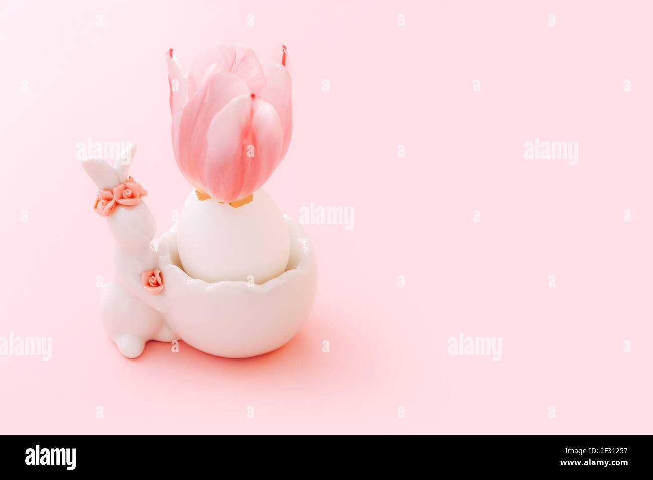 Easter egg in stand with ceramic easter bunny figurine and spring tulip ...