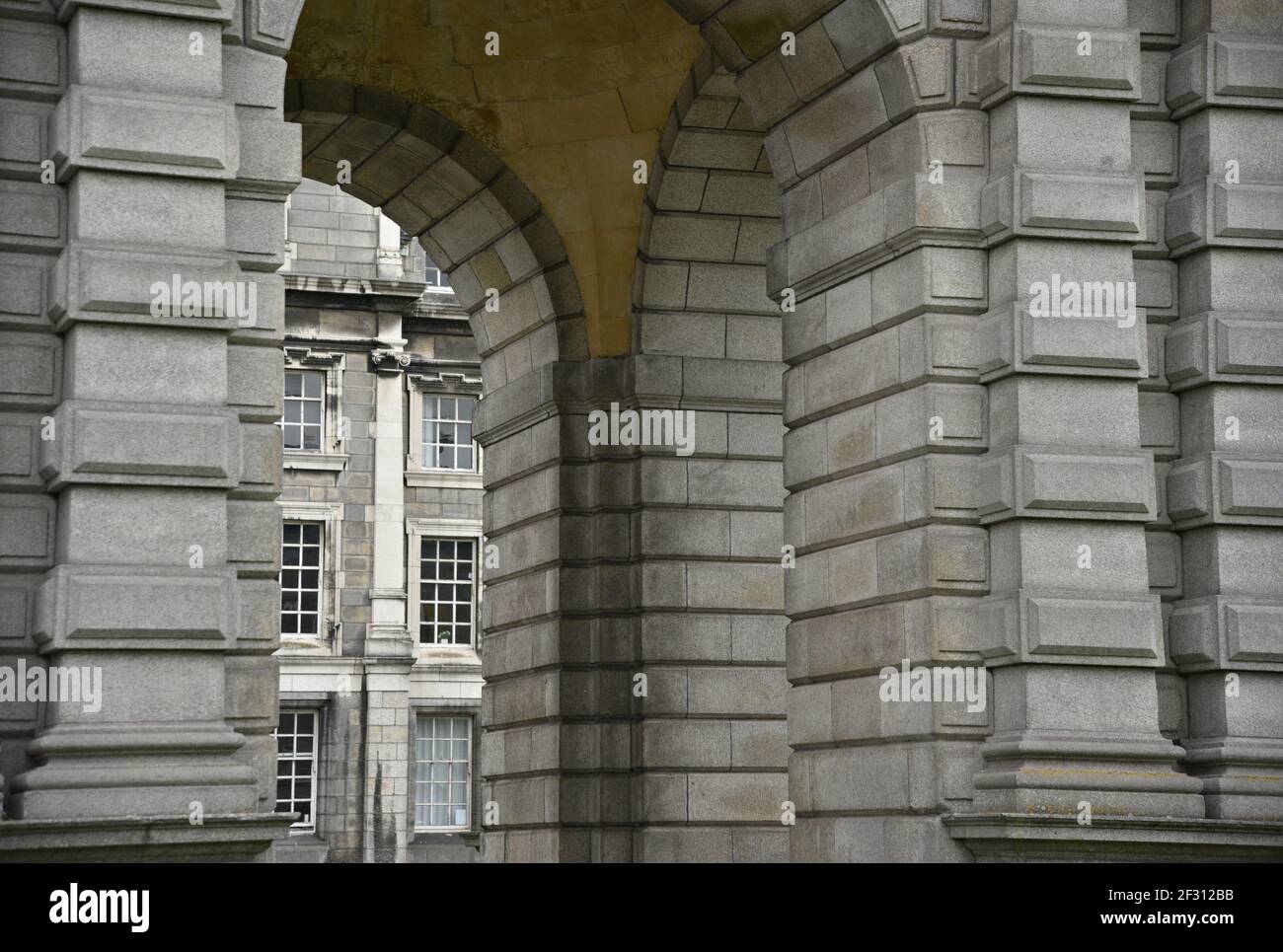 Exterior view of Trinity College through ancient stone arches in Dublin ...