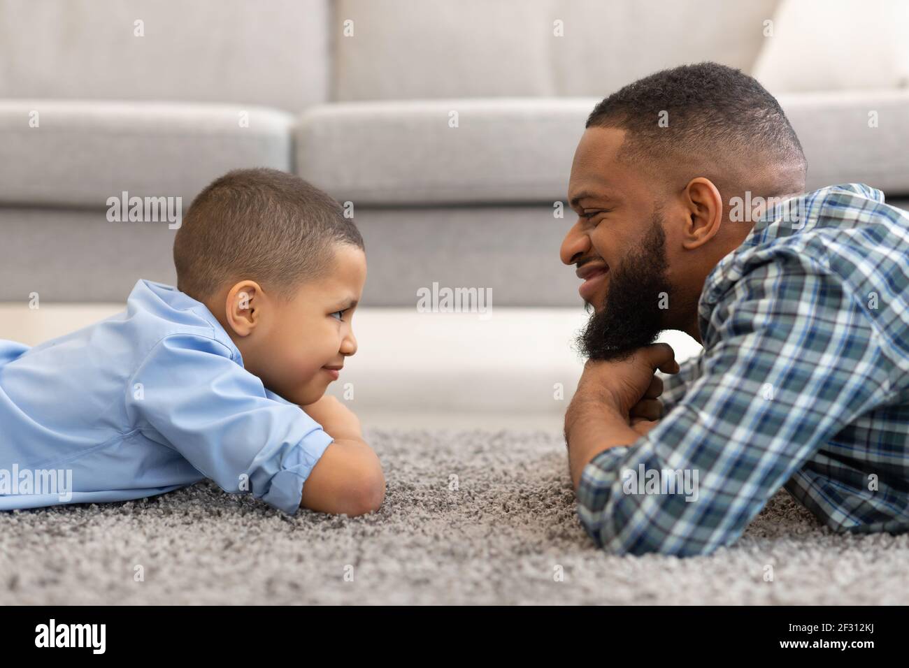African Father And Son Lying On Floor At Home, Side-View Stock Photo ...