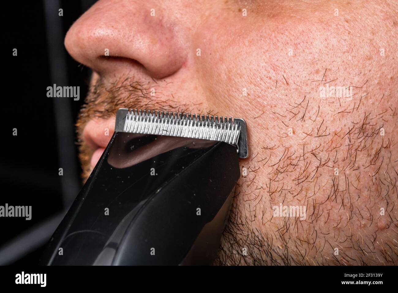 Man shaving or trimming his beard using a hair clipper Stock Photo - Alamy