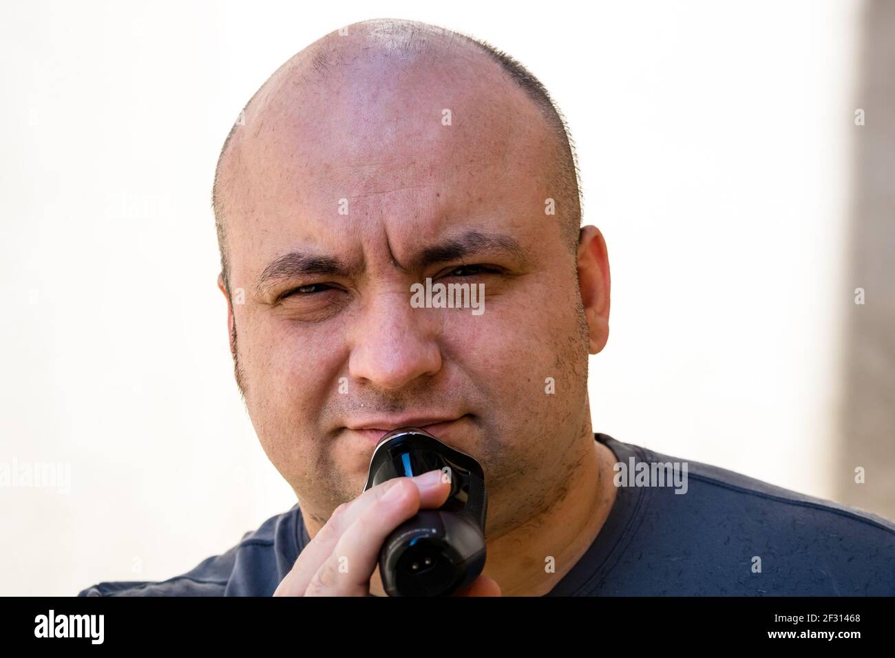 Male shaving or trimming his beard using a hair clipper or electric ...