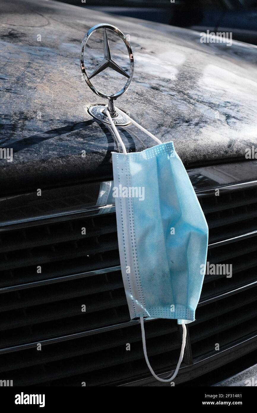 A face mask hangs from the star of a mercedes car Stock Photo - Alamy