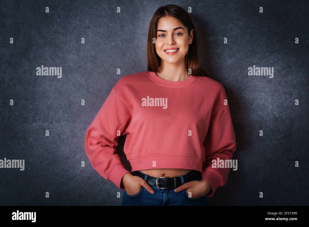 Studio portrait of beautiful young woman looking at camera and smiling ...