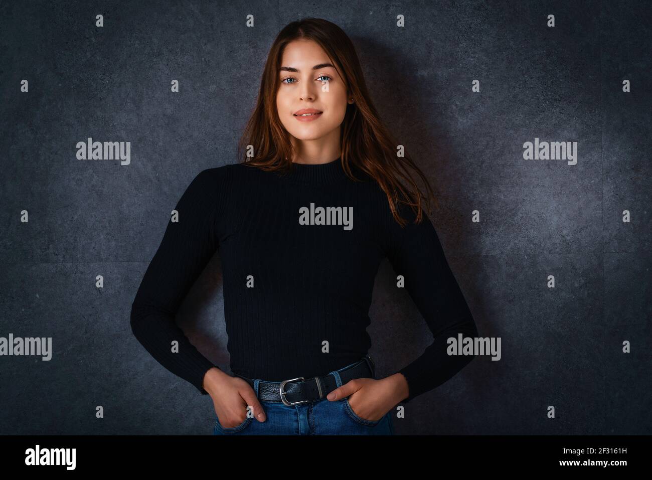 Studio portrait of beautiful young woman looking at camera and smiling ...