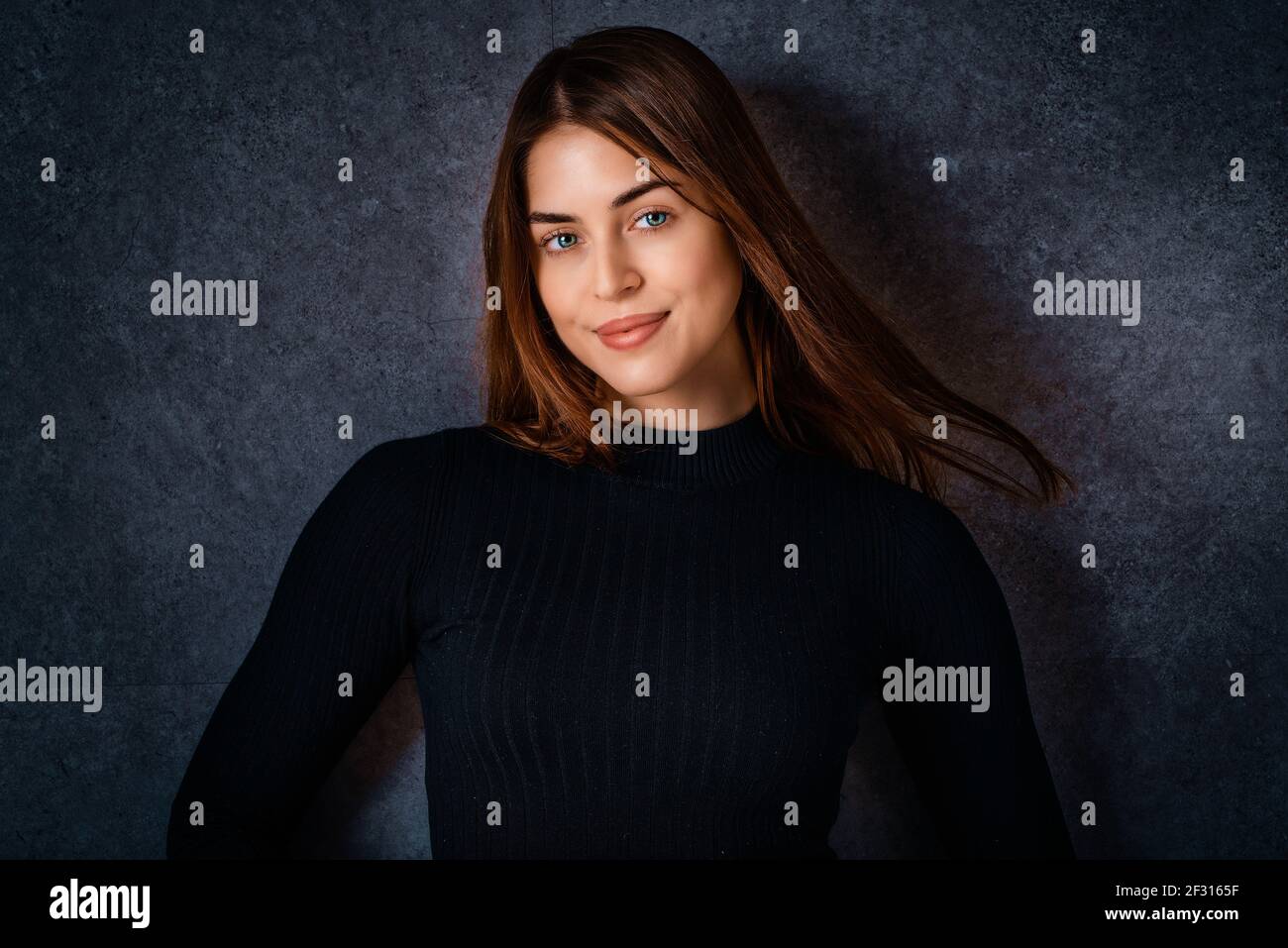 Studio portrait of beautiful young woman looking at camera and smiling ...