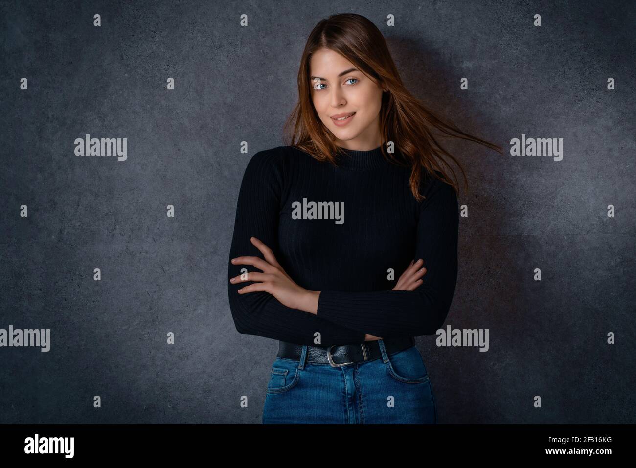 Studio portrait of beautiful young woman looking at camera and smiling ...