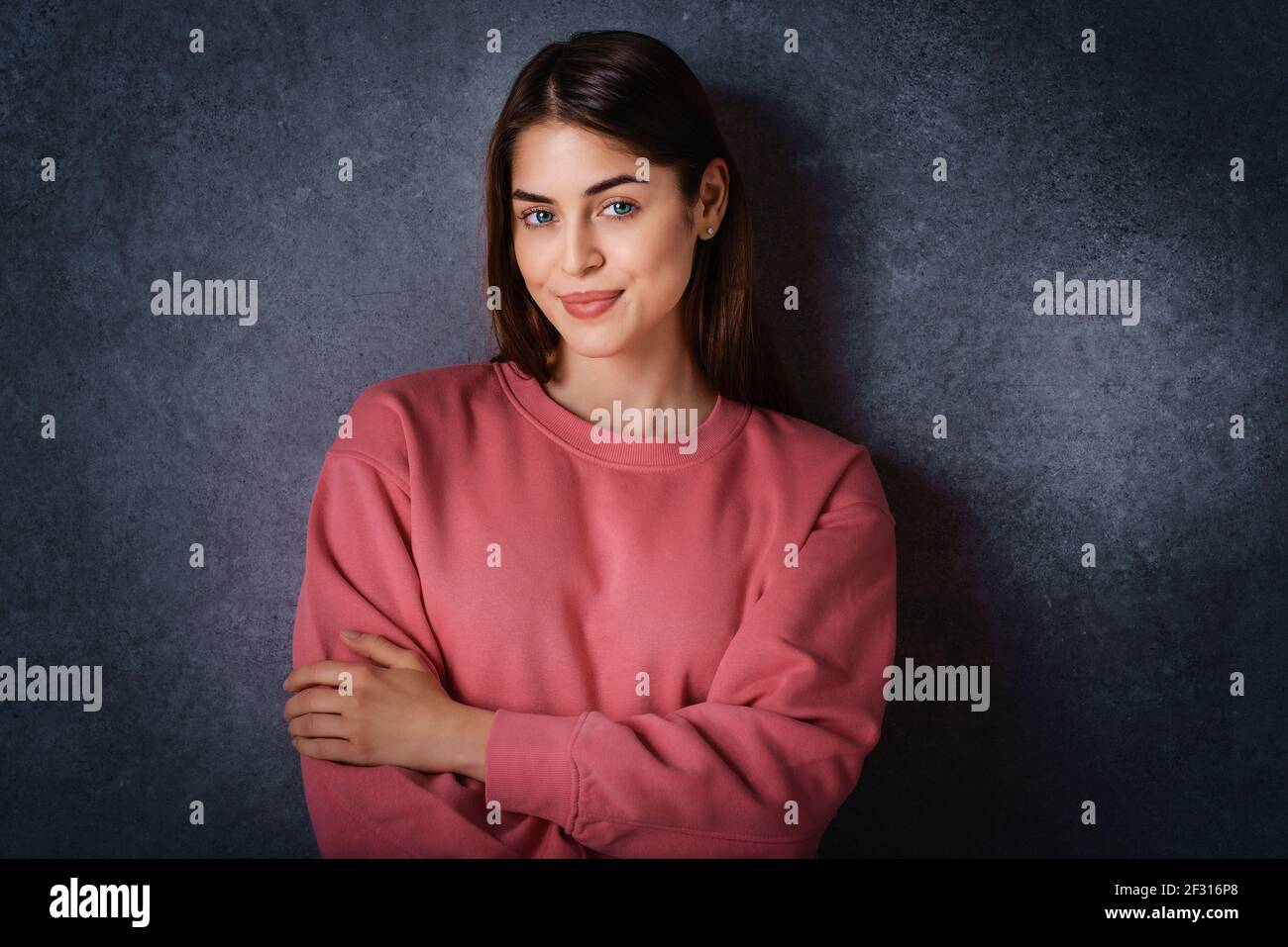 Studio portrait of beautiful young woman looking at camera and smiling ...