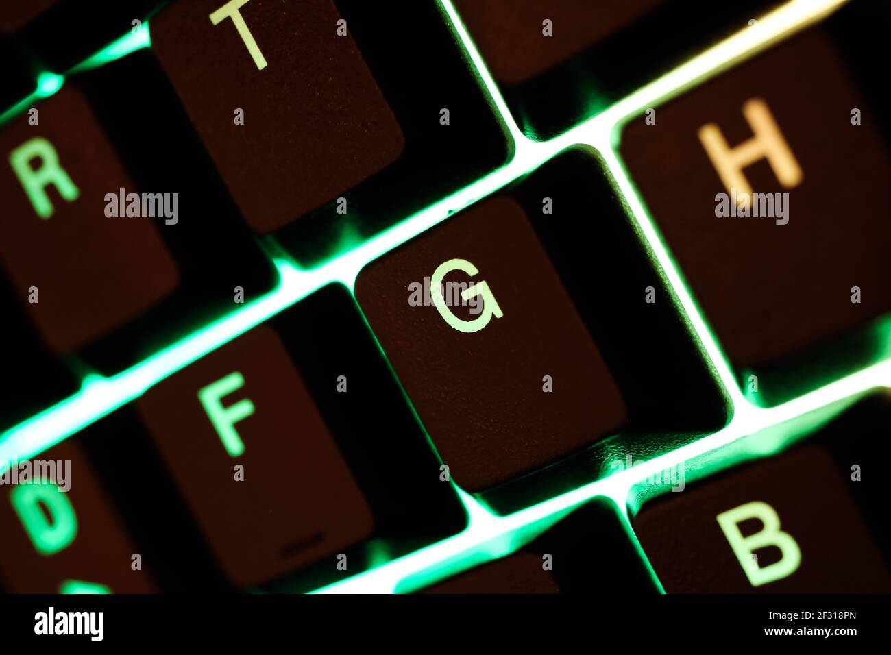 Macro closeup of green yellow illuminated keys of computer keyboard ...