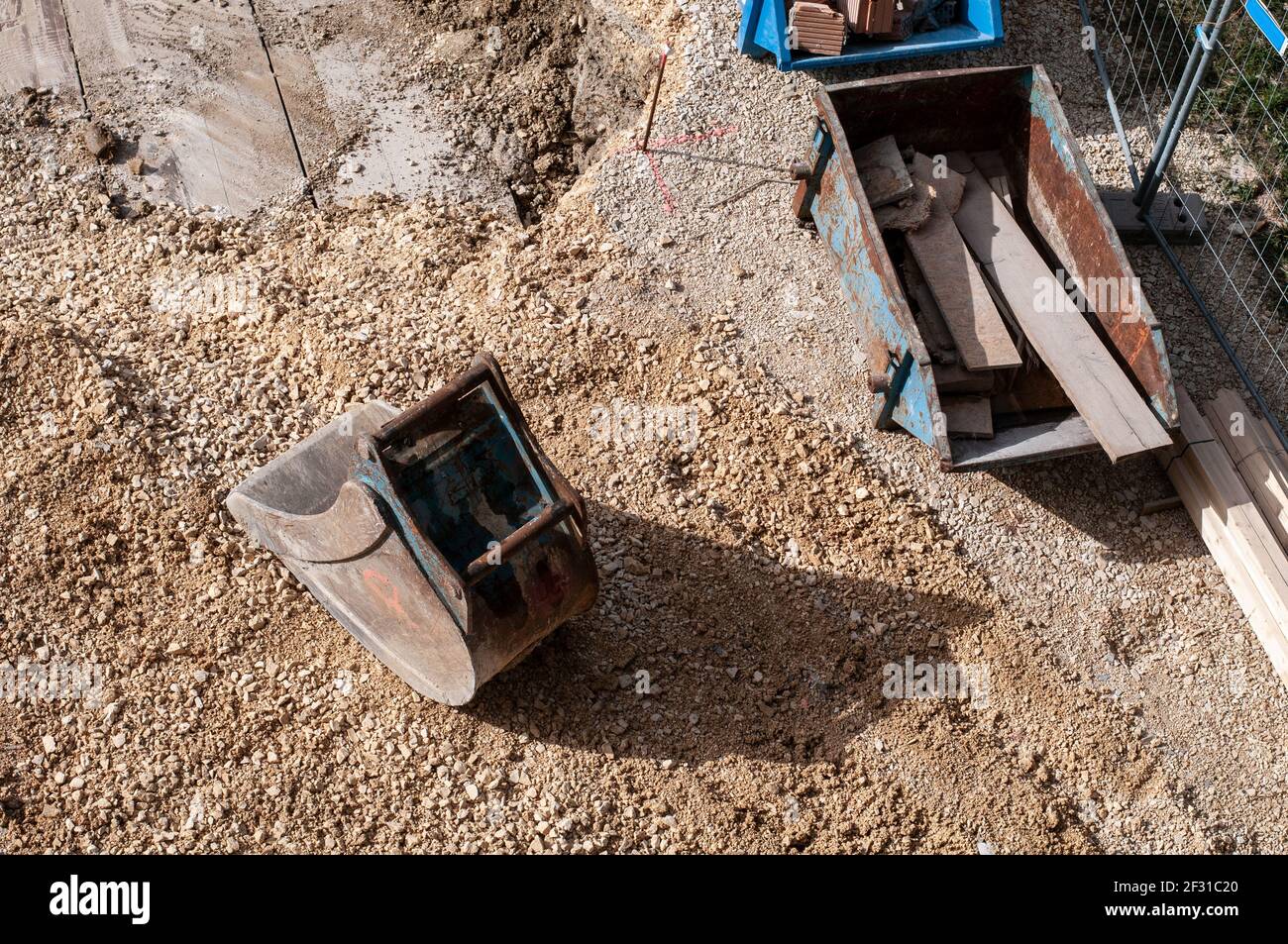 a digger bucket and a metal container filled with wooden planks at a ...