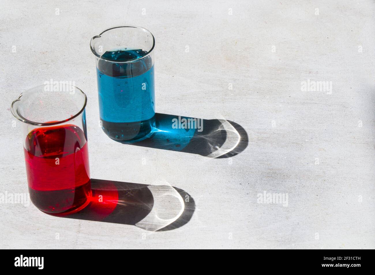 A side view of laboratory glassware filled with red and blue color ...