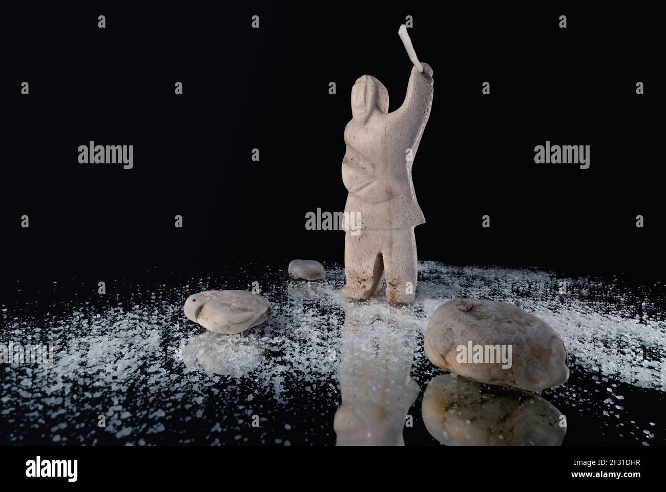 Small statue of Inuit hunter with a spear made of animal bone. Isolated ...