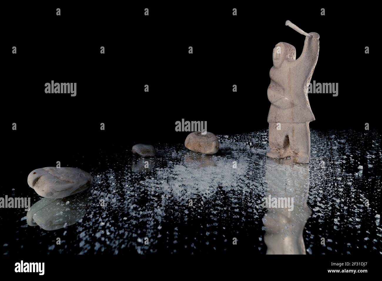 Small statue of Inuit hunter with a spear made of animal bone. Isolated ...