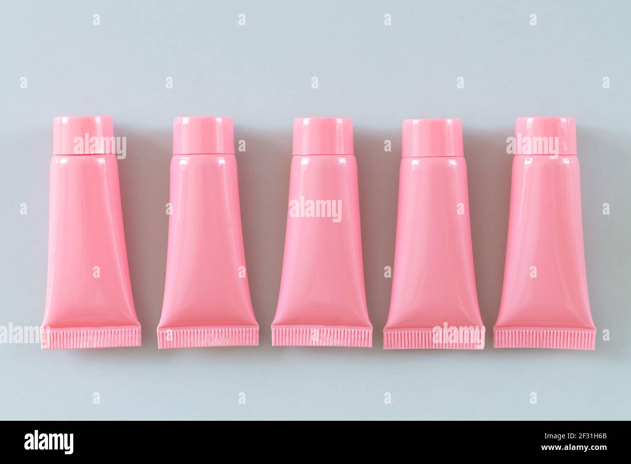 Five pink cosmetic tubes top view on gray background. Spa product ...