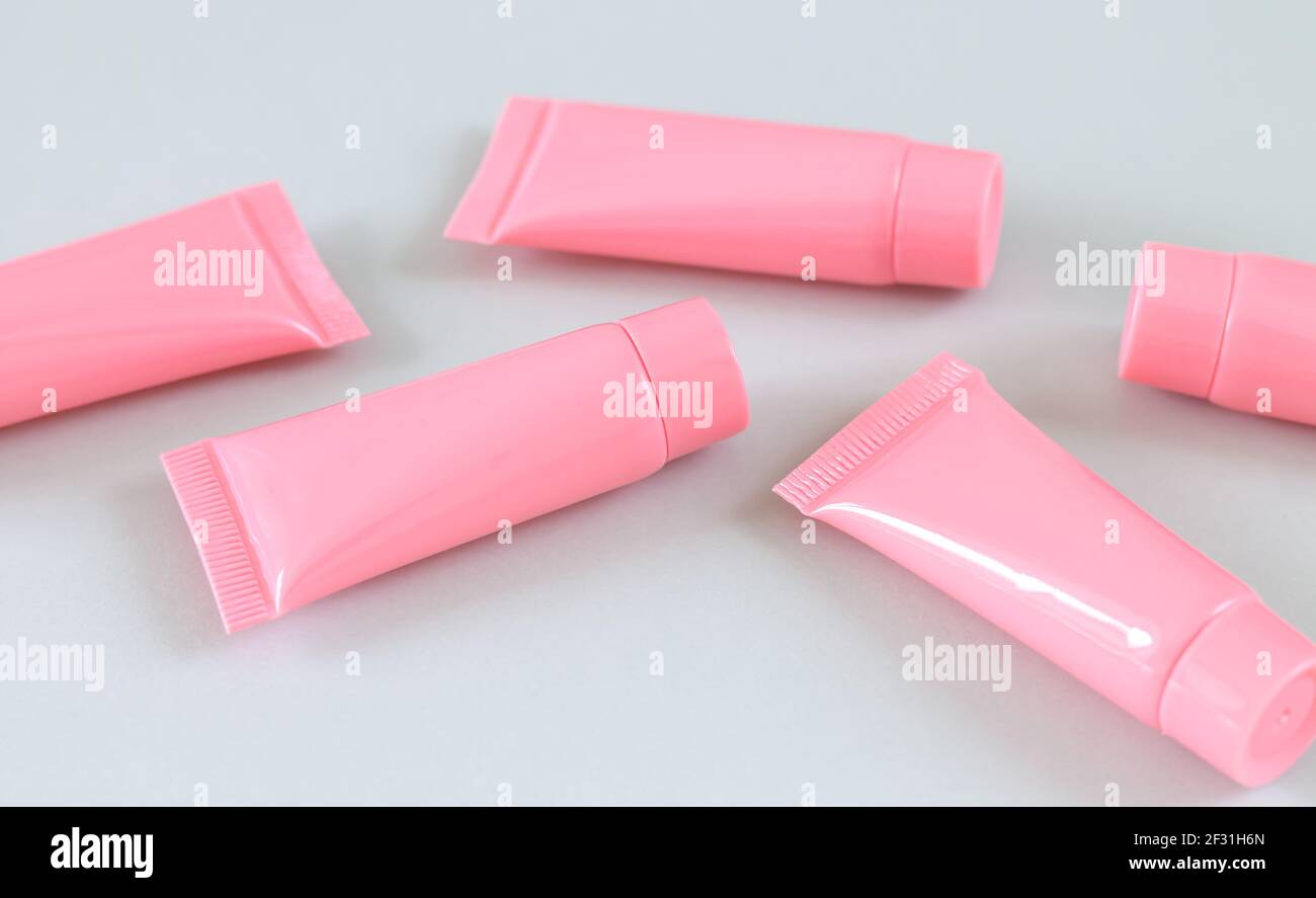 Five pink cosmetic tubes on gray background close-up. Spa product ...