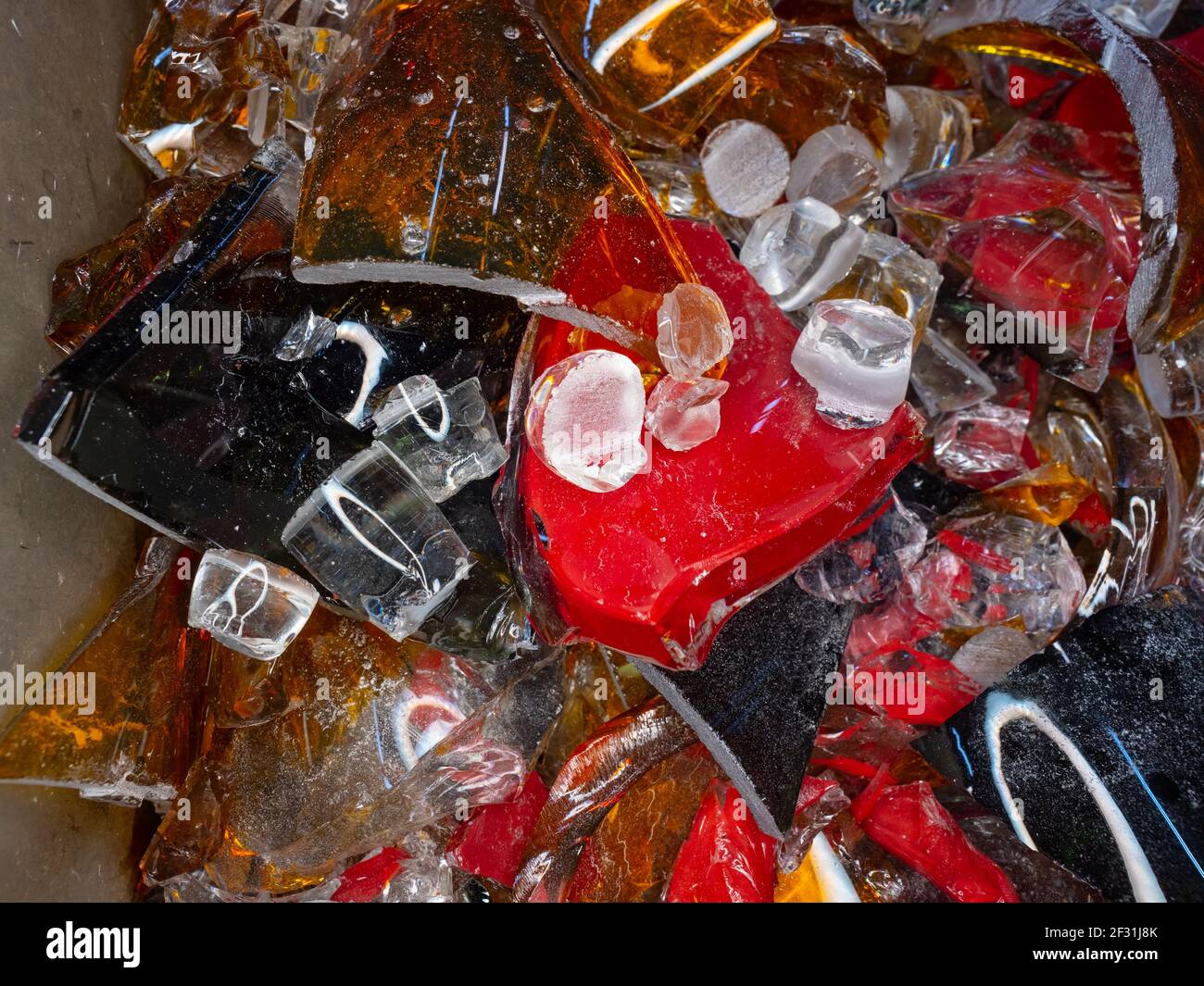 Stained glass shards and waste in a glass studio container. The hot ...