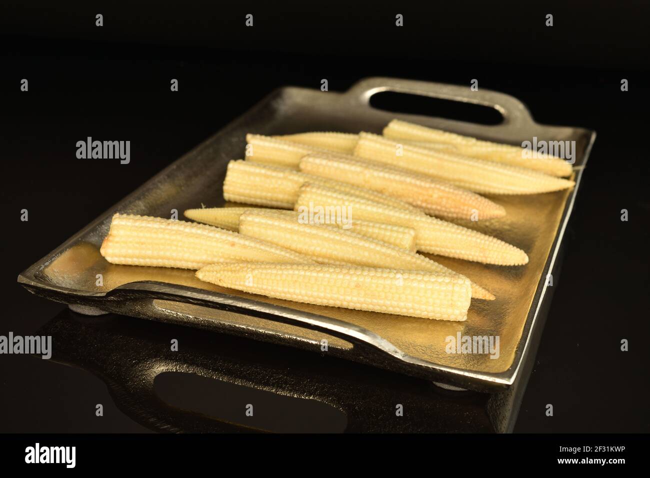 Several bright yellow ripe sweet organic mini corn on a metal tray ...