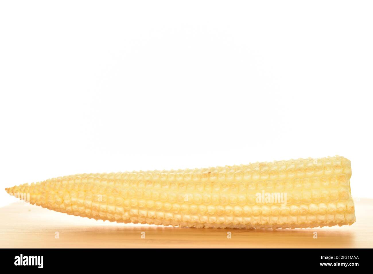 One bright yellow ripe sweet organic mini corn, close-up, on a white ...