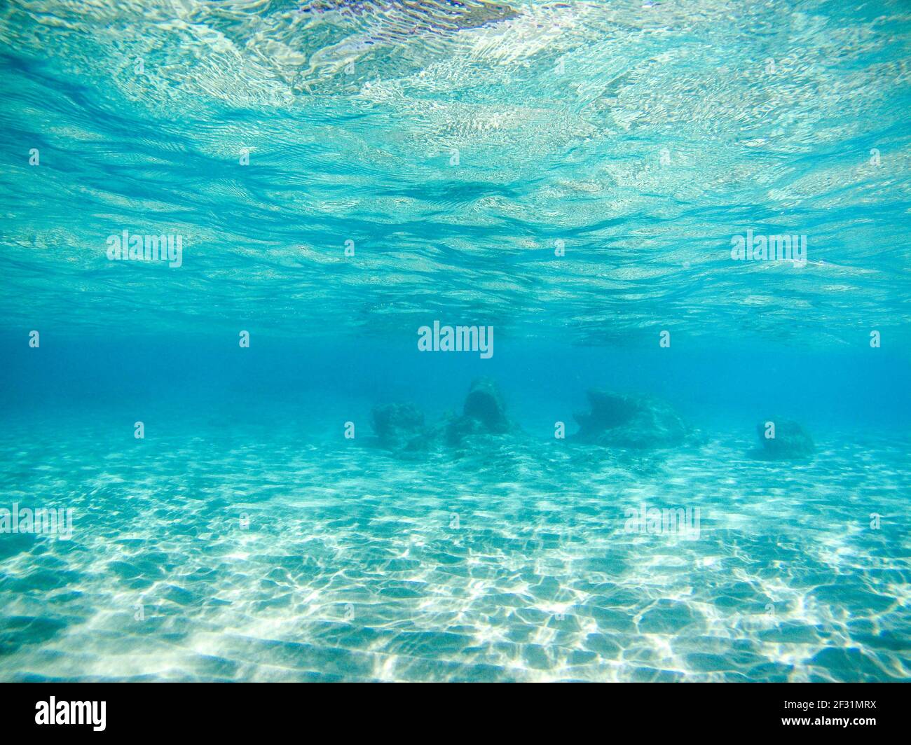 Underwater view on sand sea bottom with group of rocks in distance in ...