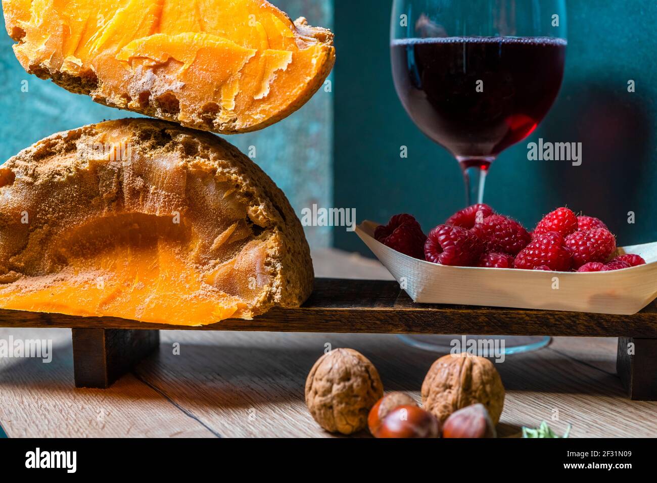 Cheese gourmet Mimolette with glass of wine, nuts, raspberry. Healthy ...