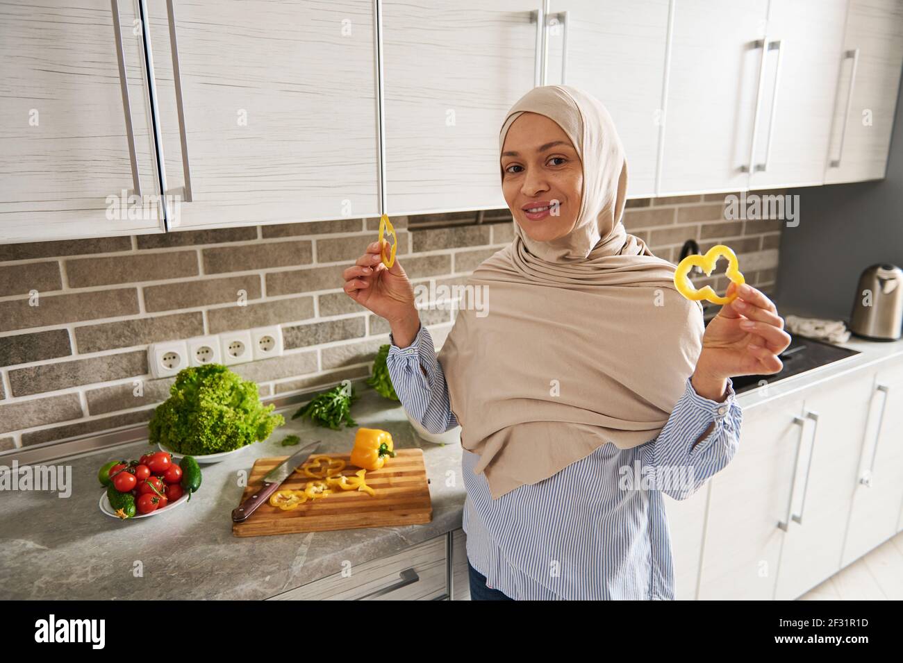 Adorable Arab Muslim woman cute holds pieces of yellow pepper in her ...