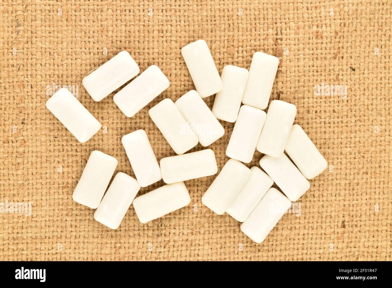 A few white fresh mint pads of chewing gum on a background of jute ...