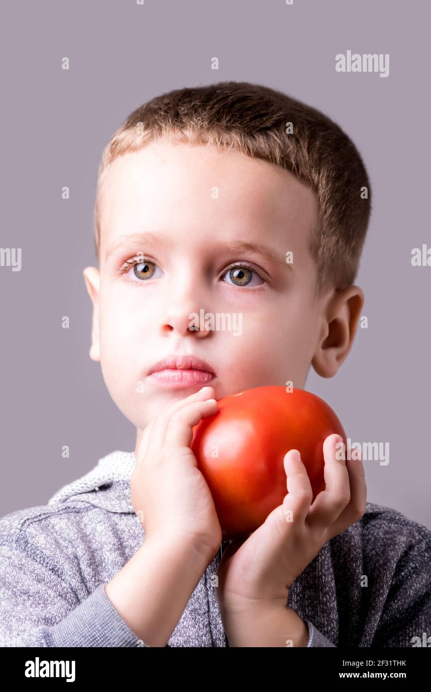 Close up of a three-year-old Caucasian boy, indoors, holding a ripe ...