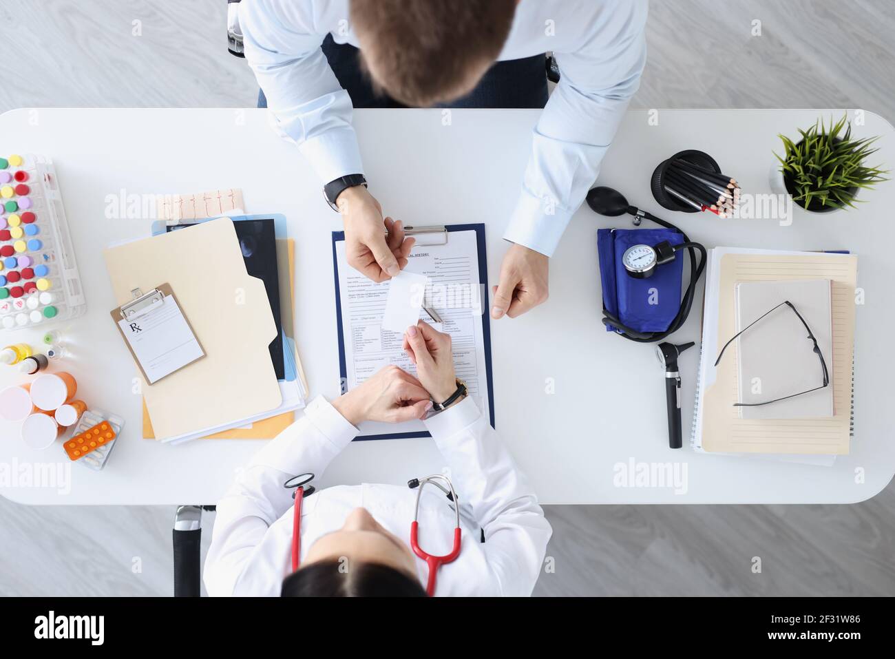 Doctor passes business card to patient at work table Stock Photo - Alamy