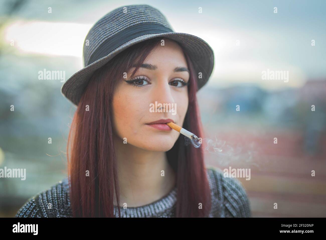 A portrait of a young caucasian smoking female with colored hair and a ...