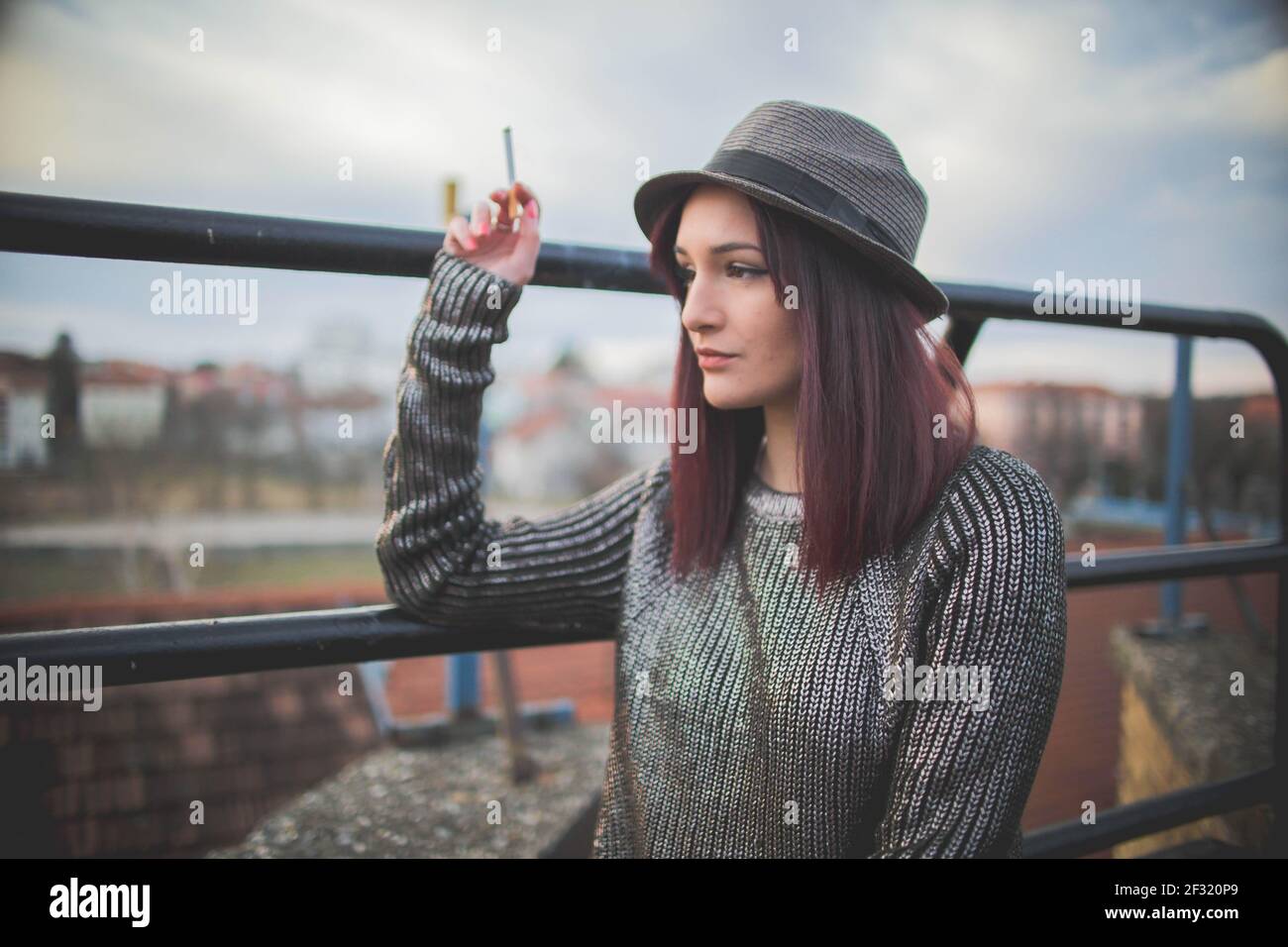 A portrait of a young caucasian smoking female with colored hair and a ...