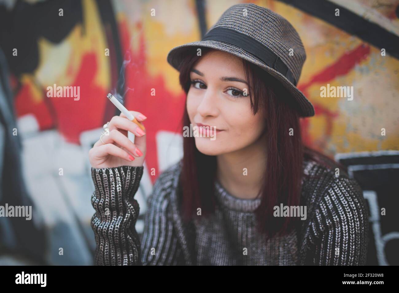 A portrait of a young caucasian smoking female with colored hair and a ...