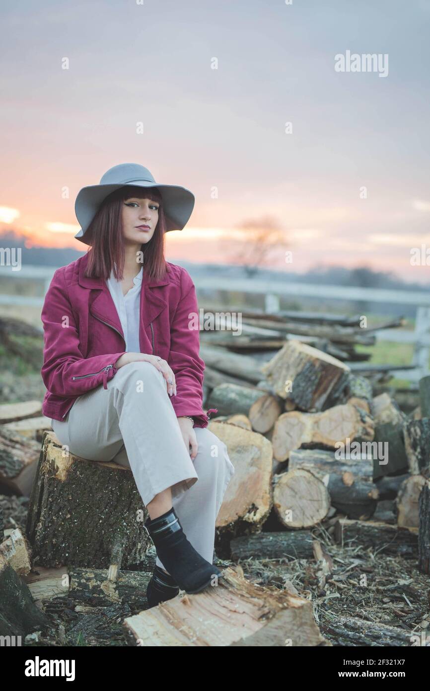 A vertical shot of a young caucasian female in an elegant hat and pink ...