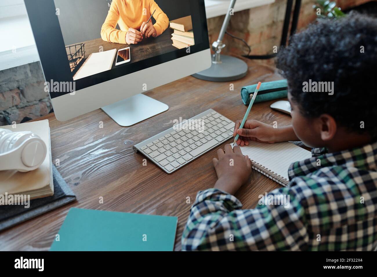 Little boy sitting by table in front of computer monitor during online ...