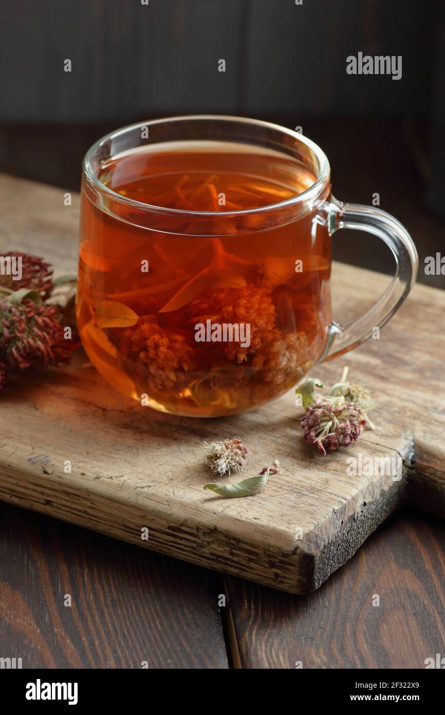 Red clover tea in glass cup on wood on rustic background of wicker ...