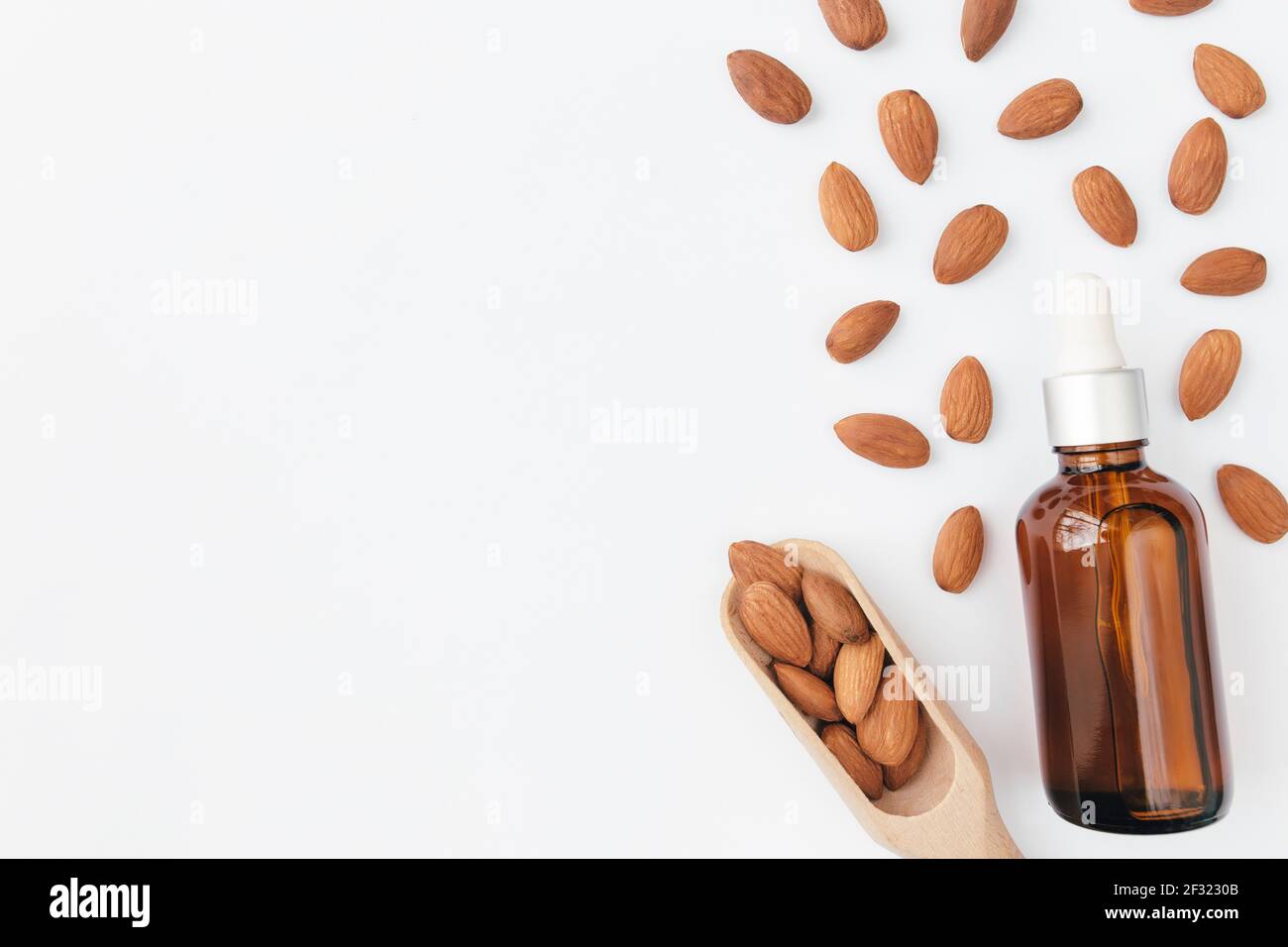 Almond essential oil in glass bottle with spoon, raw almond nuts ...