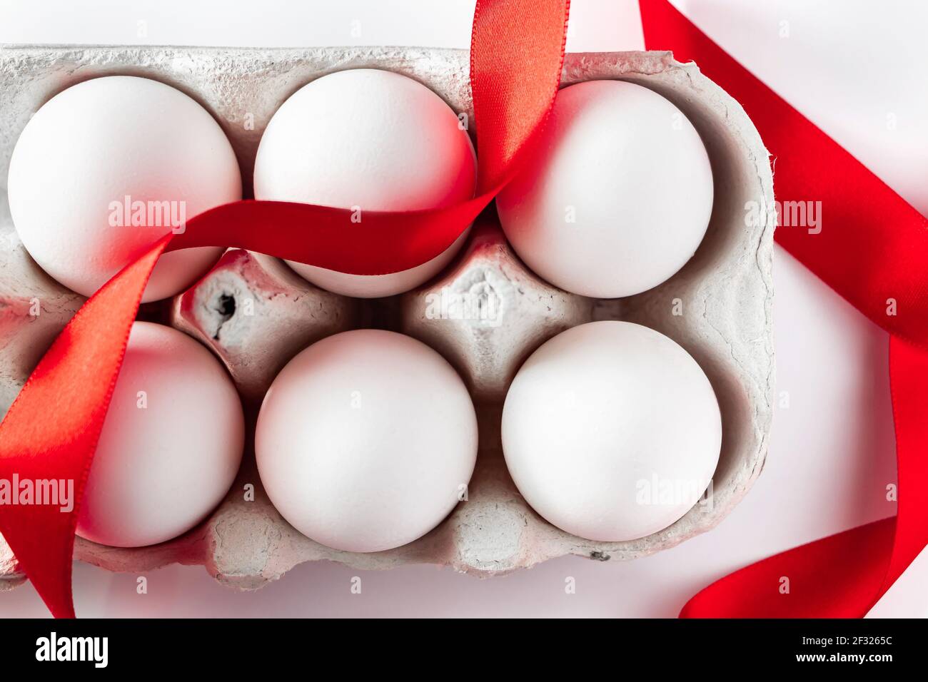 White easter eggs in eco-friendly cardboard box with red festive silk ...