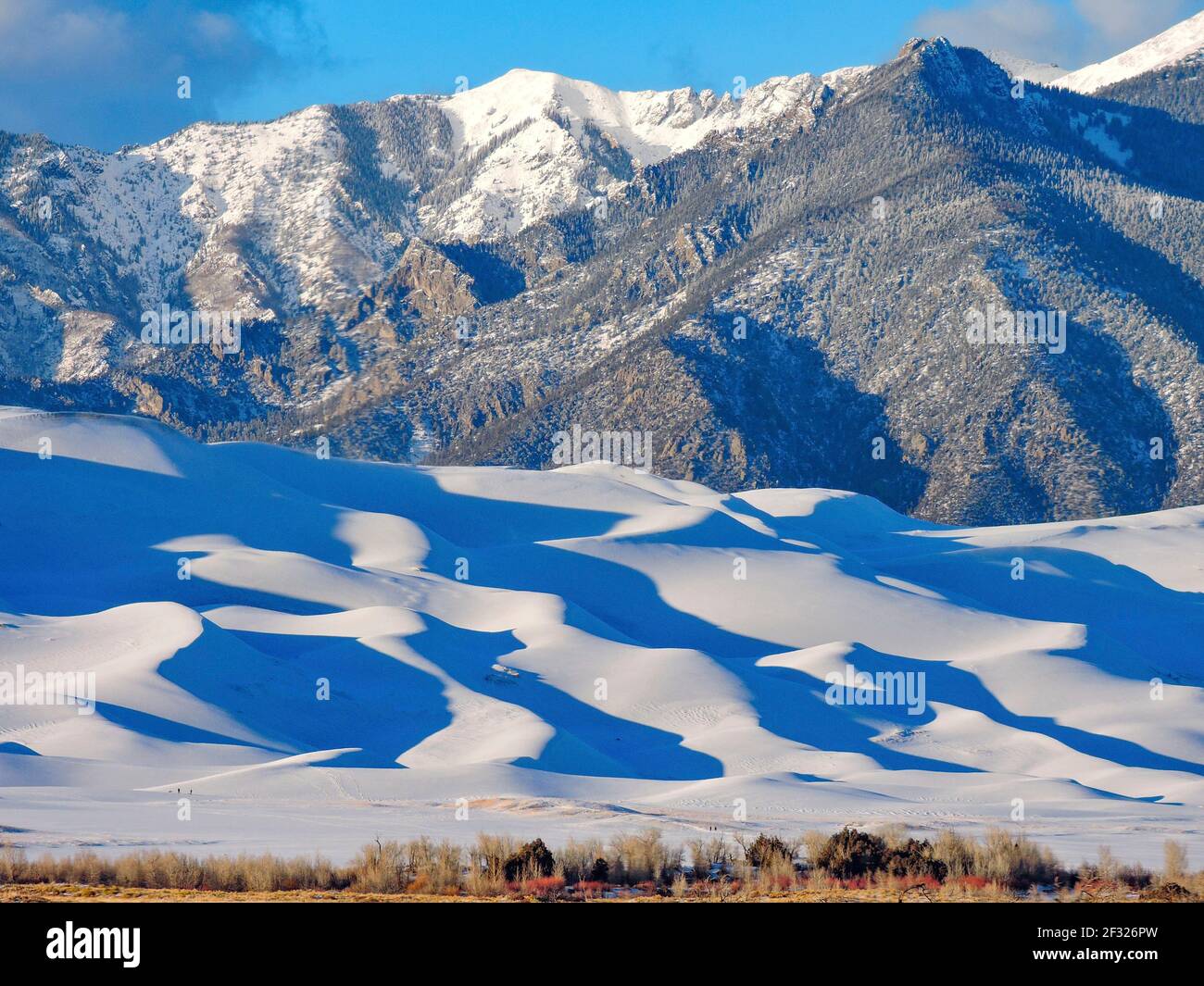 Snow covers sand dunes with the Sangre de Cristo Mountains at the Great ...