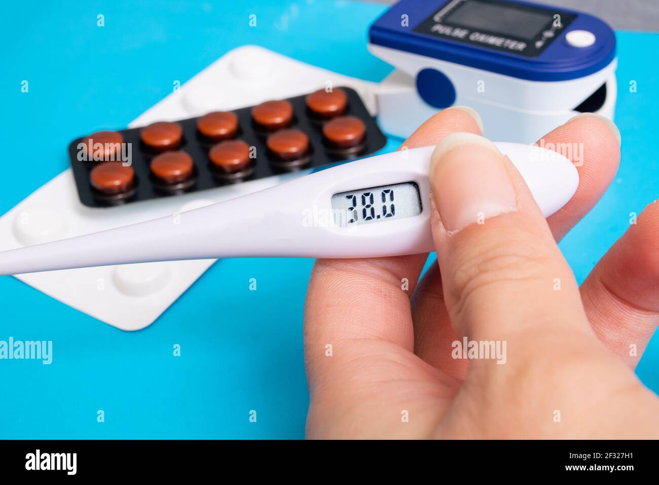 High temperature on a thermometer and pills on a blue background Stock ...