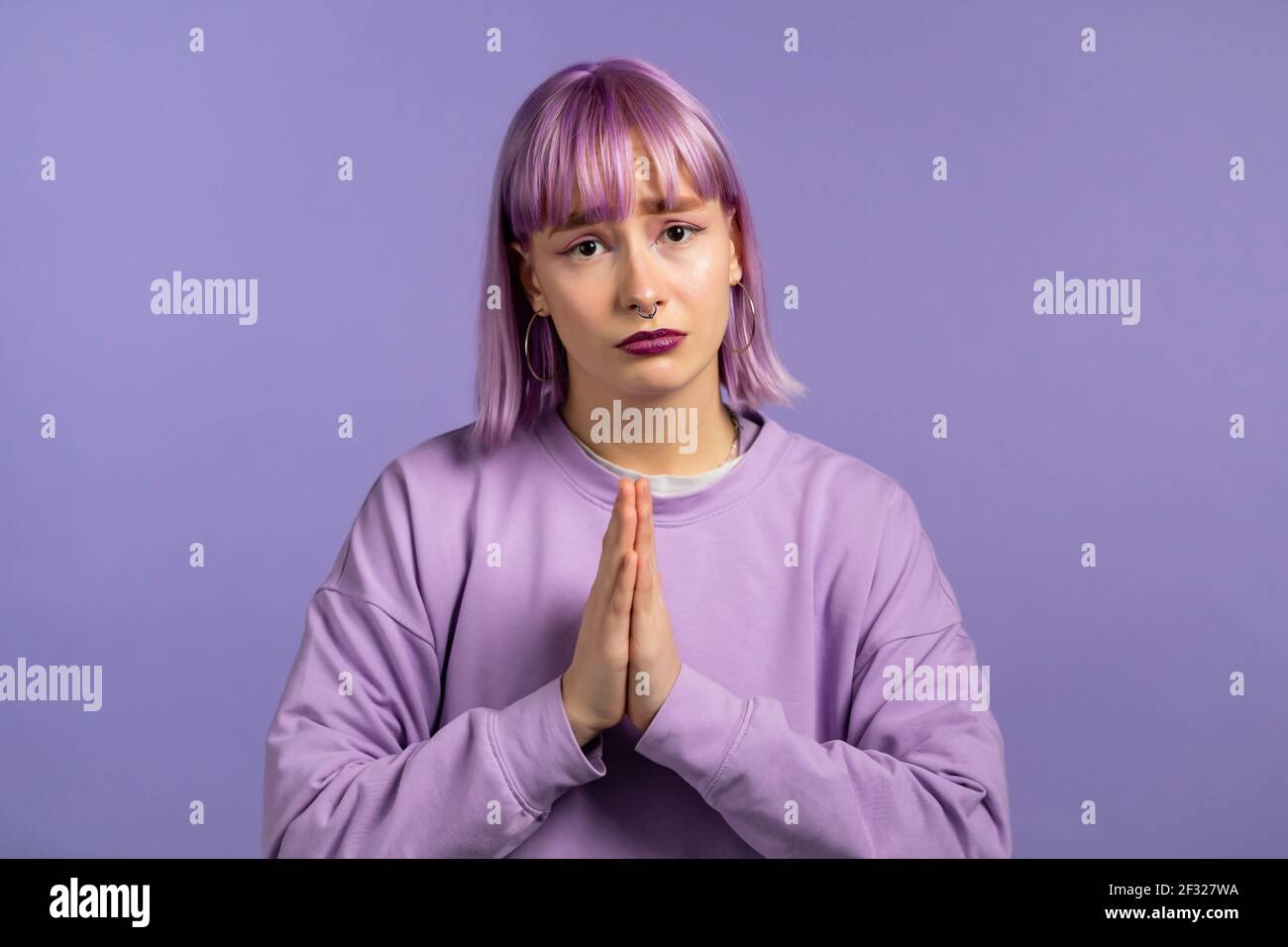 Pretty trendy woman praying over violet background. Girl with dyed ...