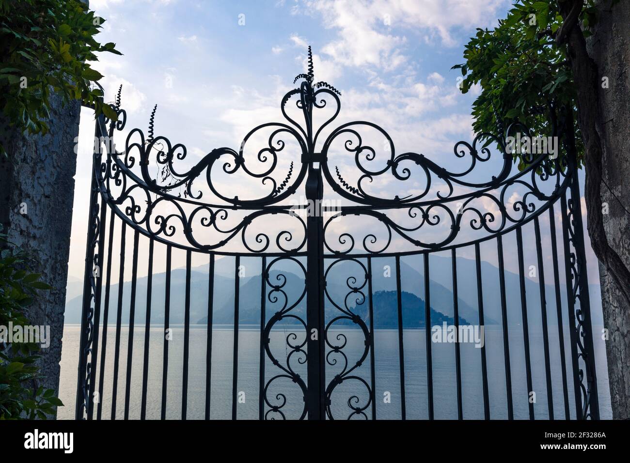 Italy,Varenna,looking through a garden iron gate towards Lake Como ...
