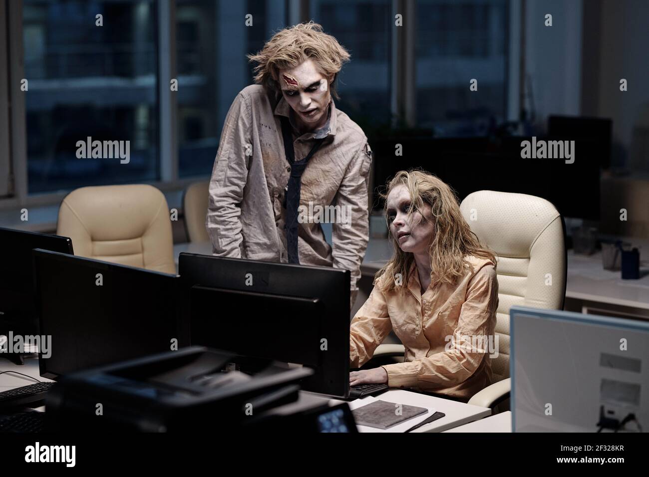 Young spooky zombie businessman standing next to female colleague ...